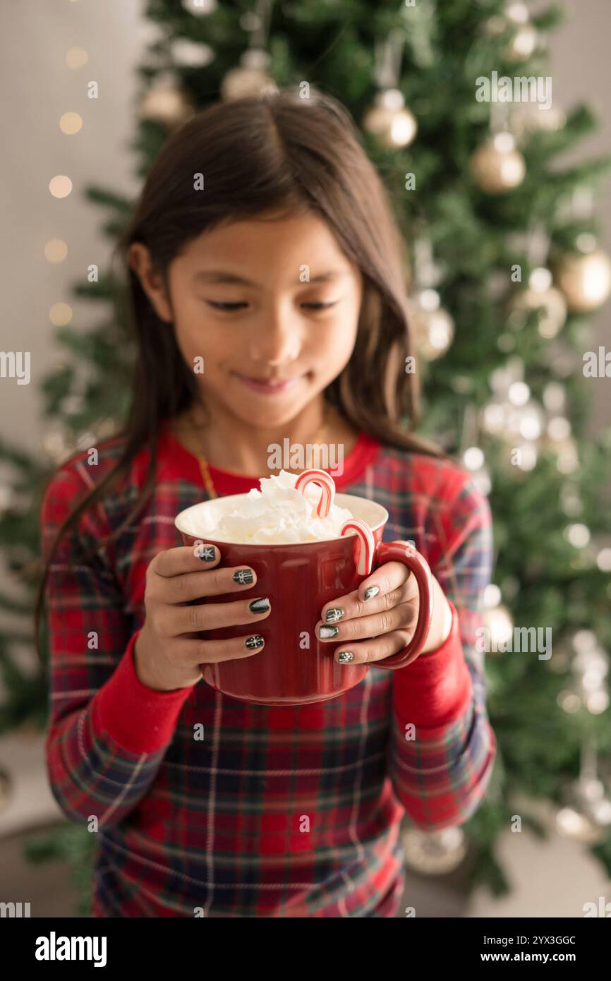 Girl looking at her cup of hot chocolate with candy canes Stock Photo ...