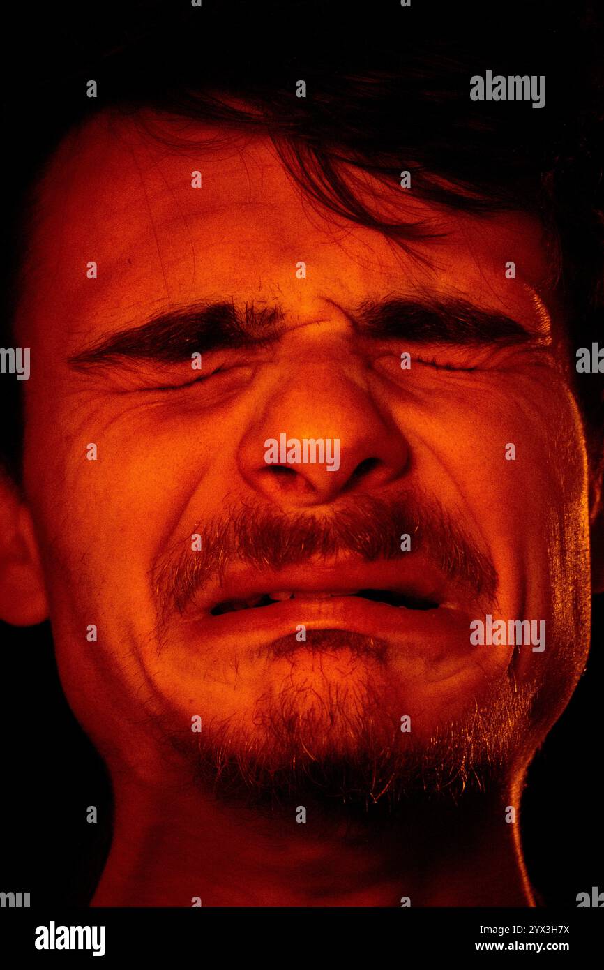 Studio portrait of a young ma with a strange emotion akin to madness or ...