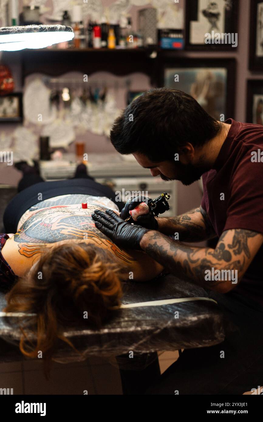Tattoo artist doing Japanese traditional tattoo on woman's back Stock ...