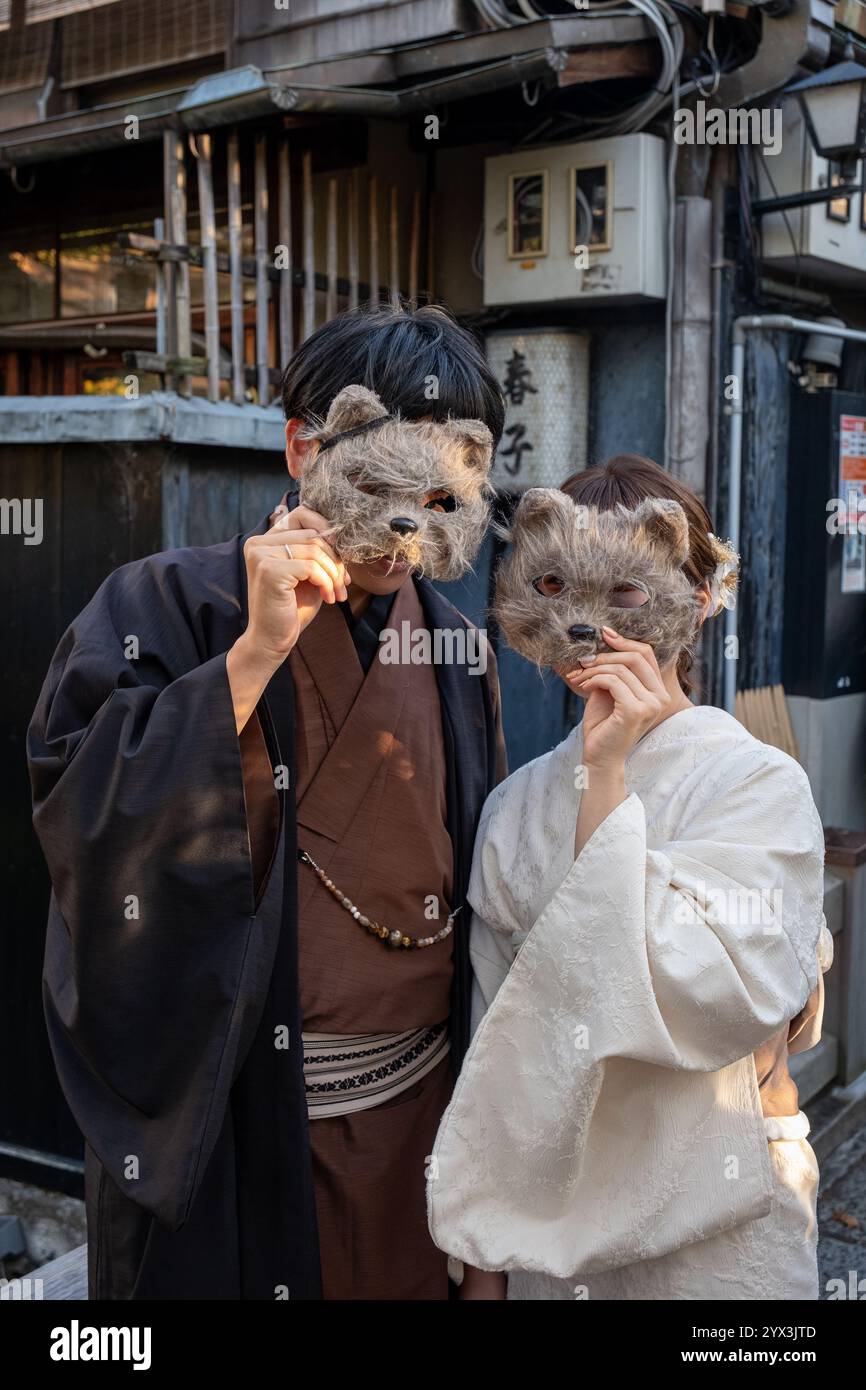 A young couple in traditional Japanese dress hold fox masks to t Stock ...