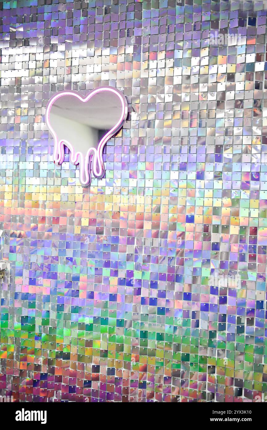 Neon heart mirror dripping over reflective, iridescent tile wall Stock ...