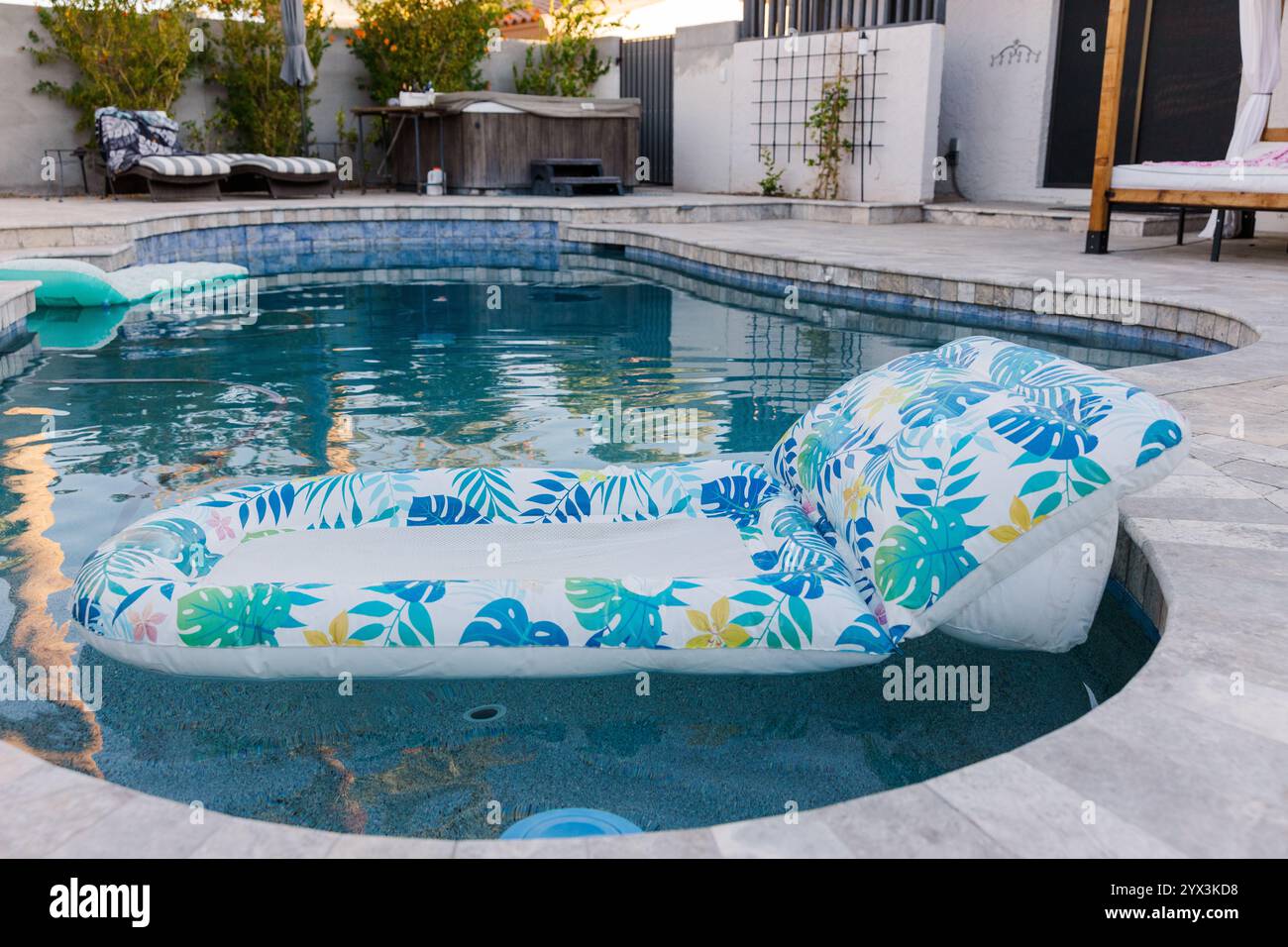 Tropical-patterned pool float on a serene backyard swimming pool Stock ...