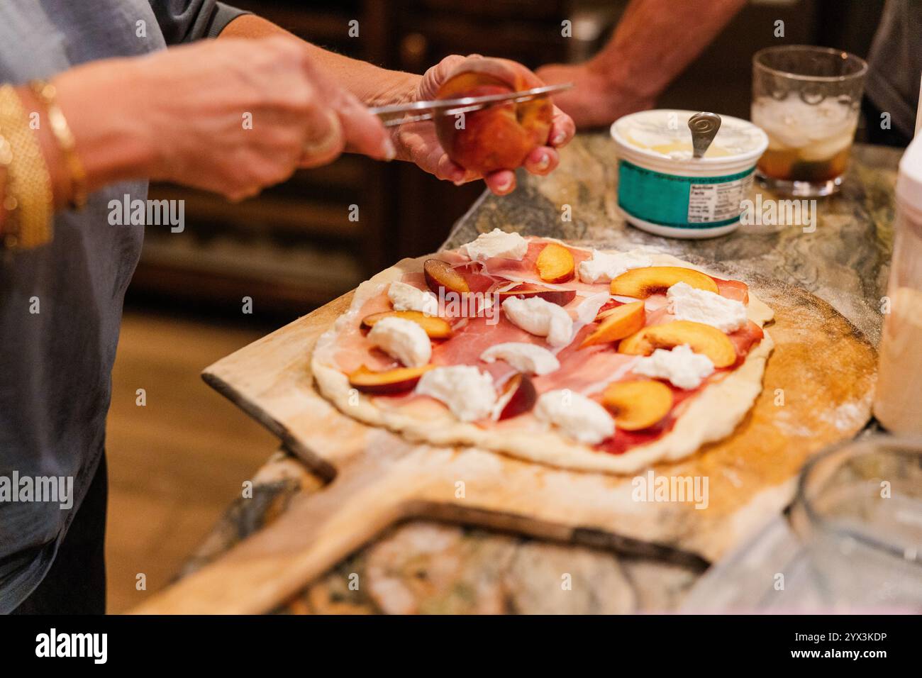 Assembling a pizza with prosciutto, peaches, and ricotta cheese Stock ...