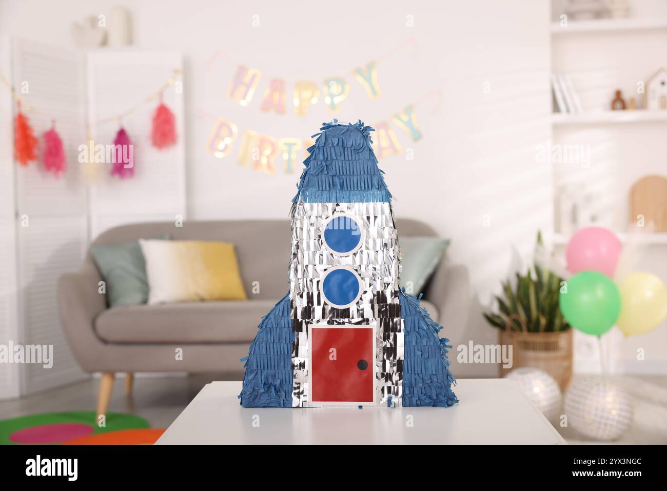 Bright pinata in shape of rocket on table in festive decorated room ...