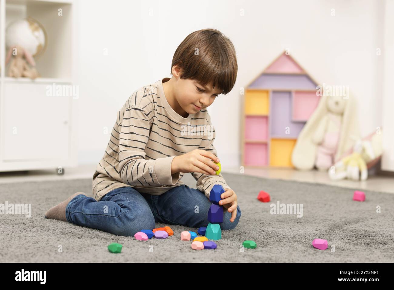 Boy playing with balancing stones on floor indoors Stock Photo - Alamy