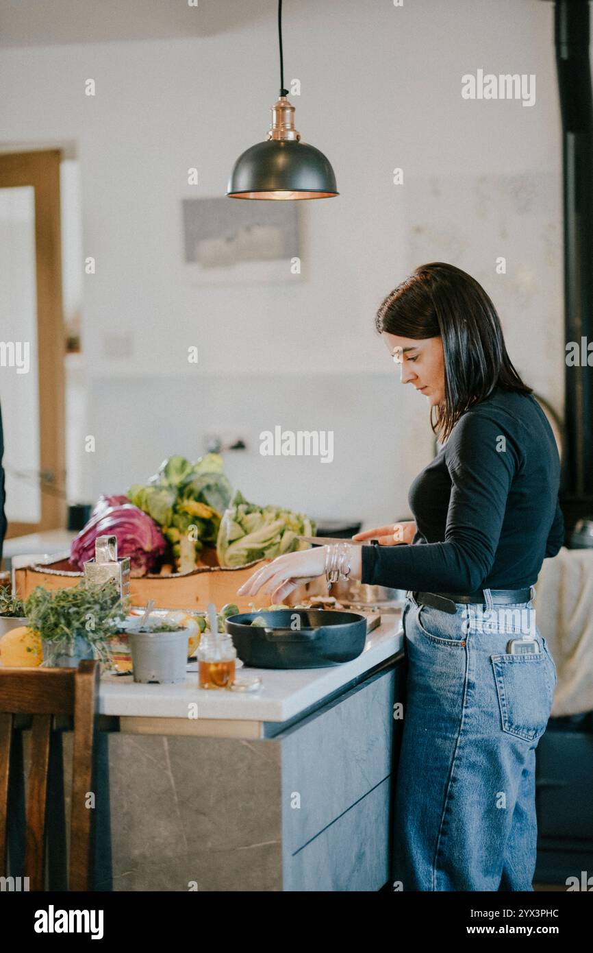A woman is cooking in a kitchen with a black and white background. She ...