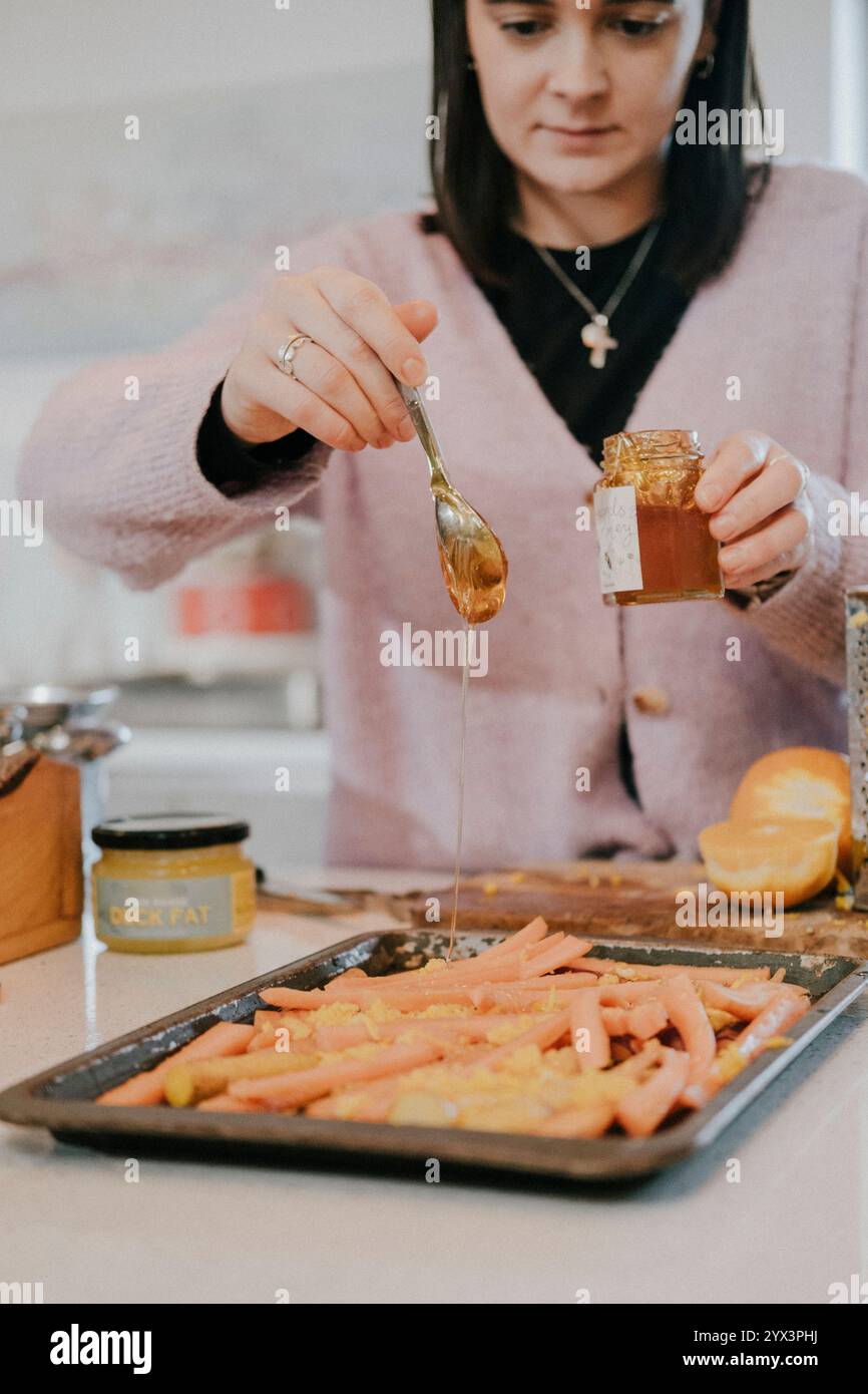A woman is making a dessert with honey and carrots. She is pouring ...