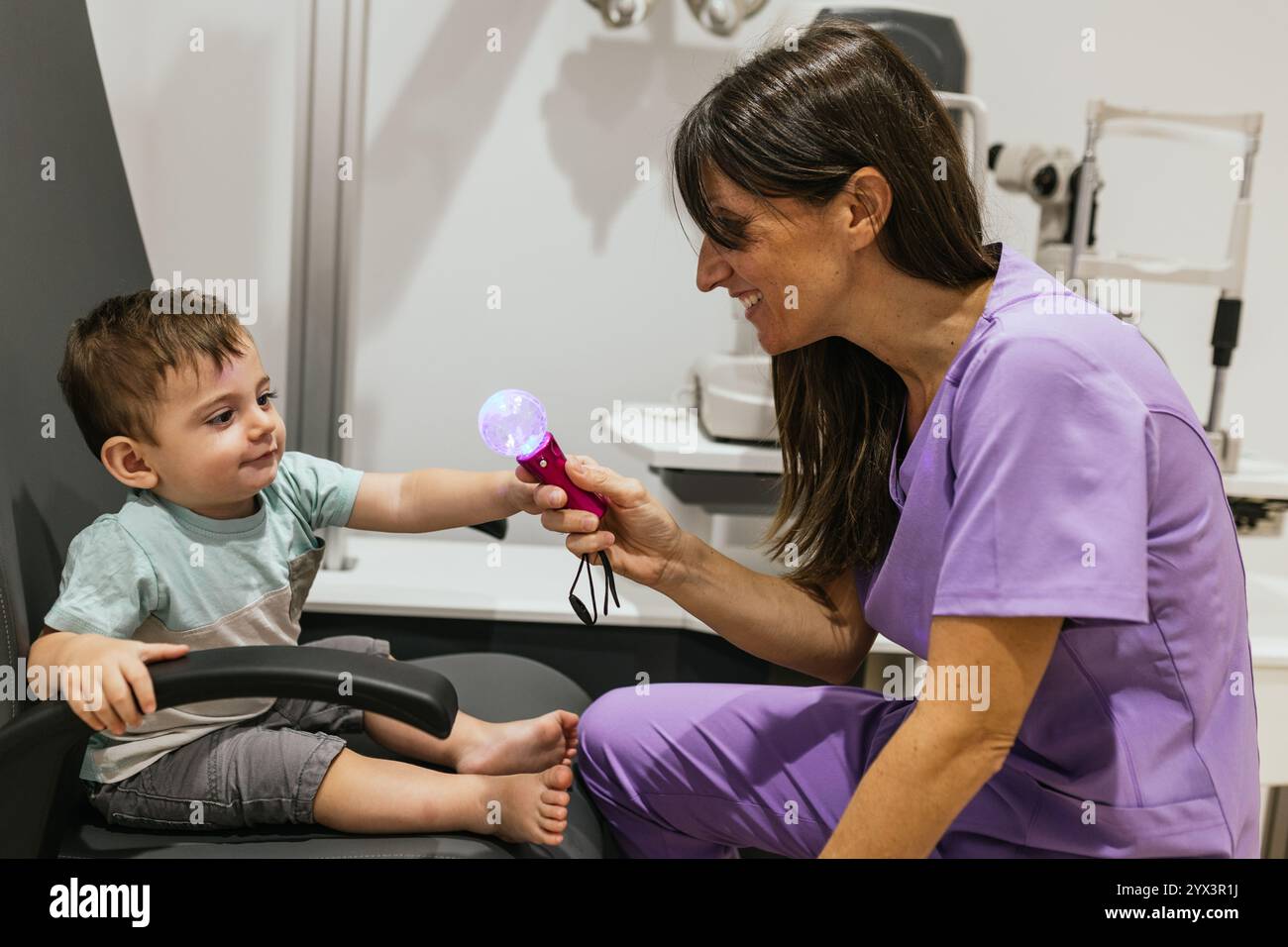 Optometrist doing eyesight check to child using colorful flashing toy ...