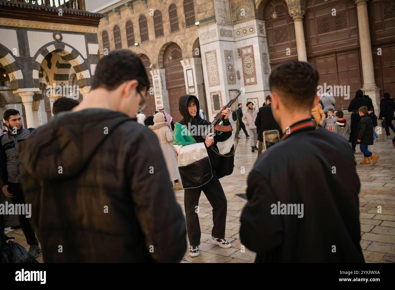 A young man poses holding a gun before Friday prayer at the Umayyad ...