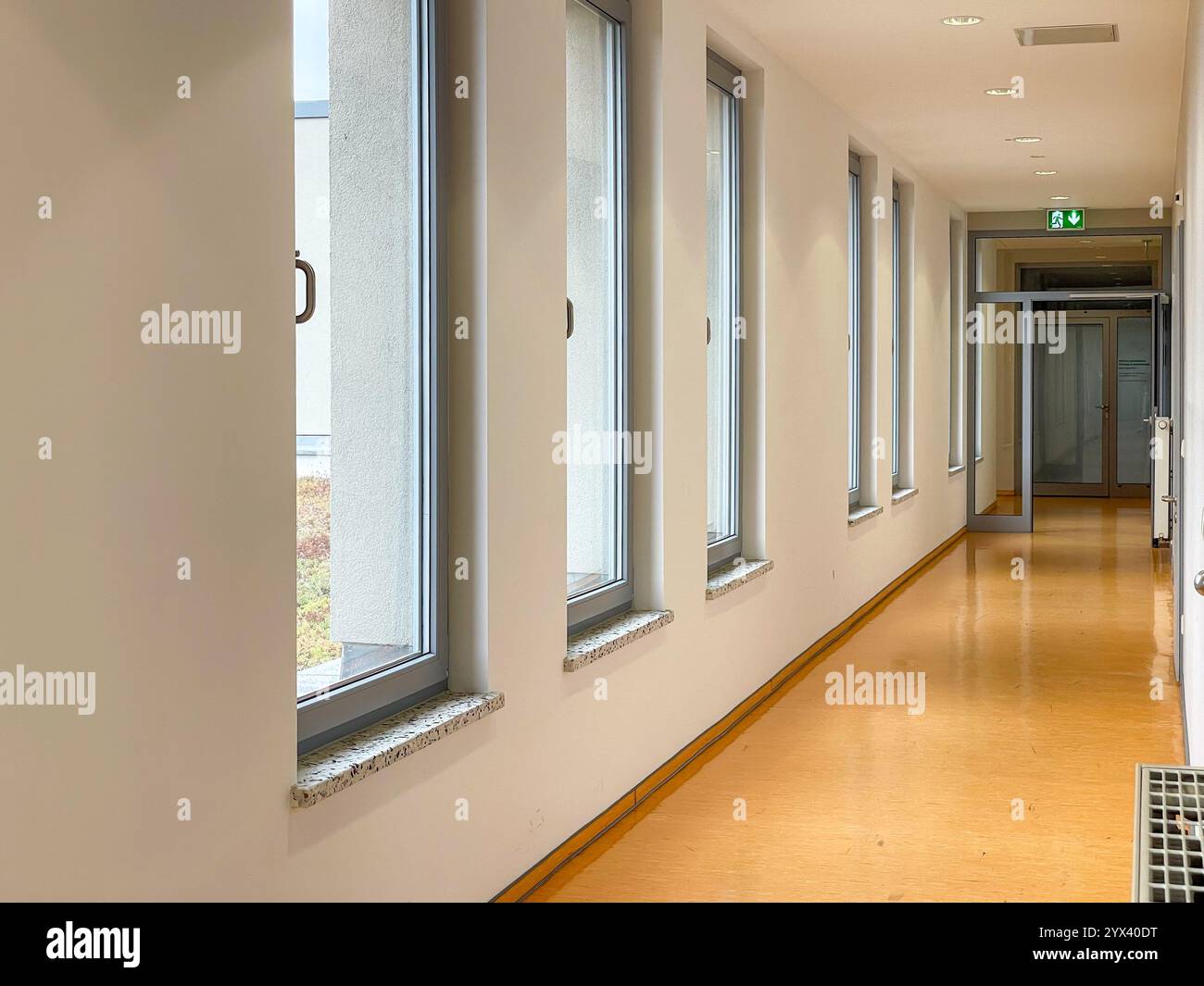 A hallway with a row of windows and a door. The windows are open and ...