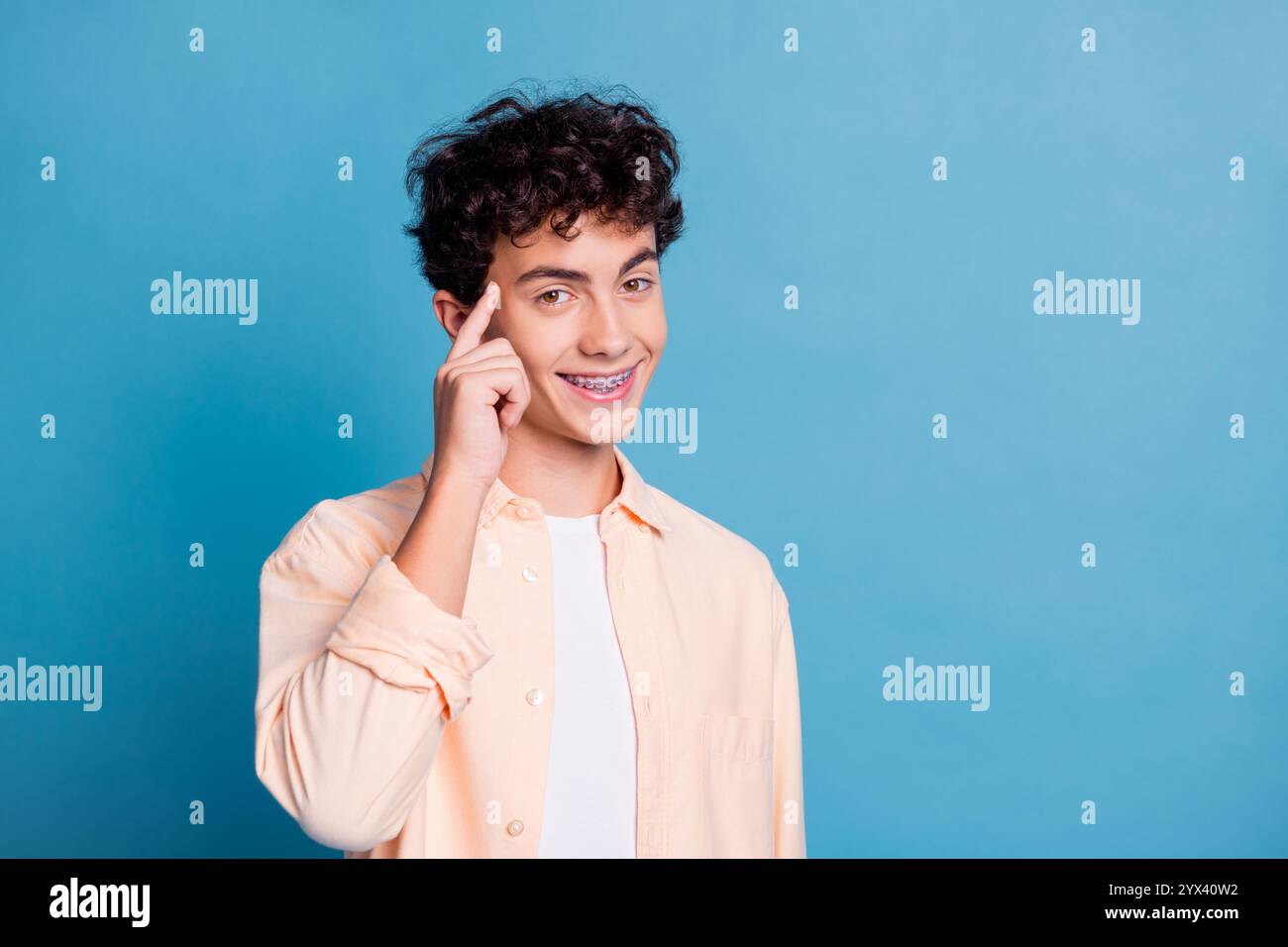 Charming young man with curly hair posing against a vibrant blue ...