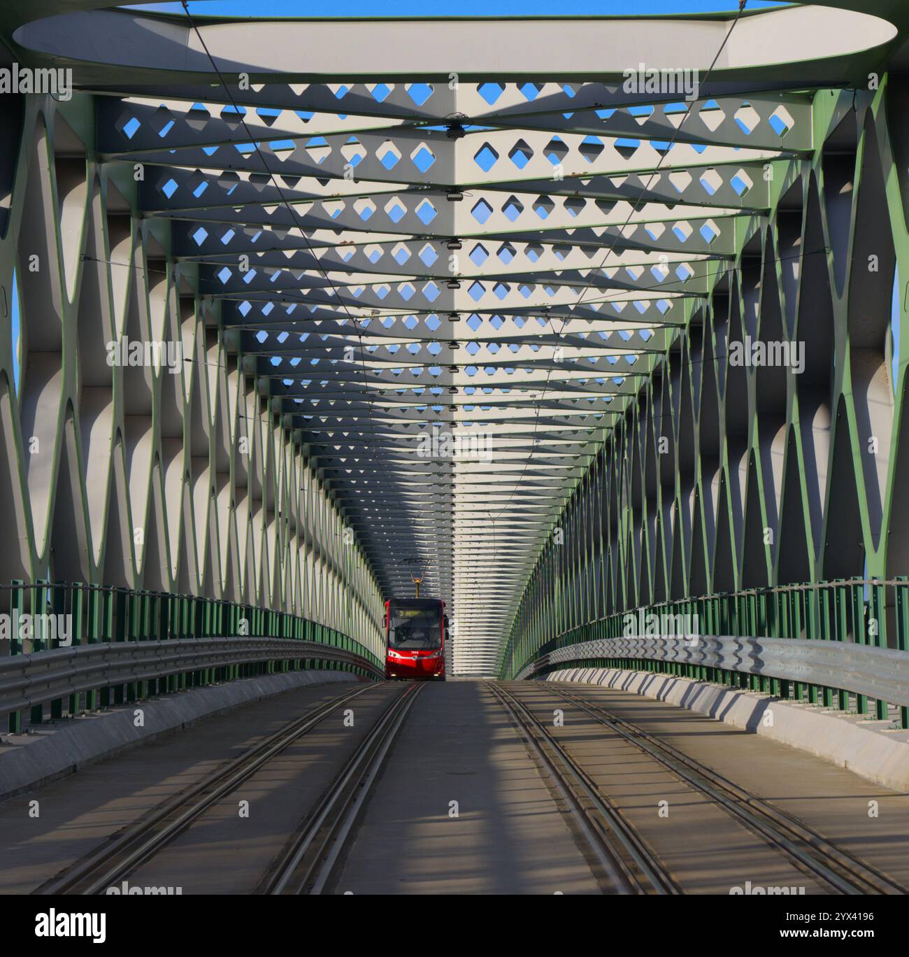 Symmetrical view of a tram crossing a steel bridge with intricate ...