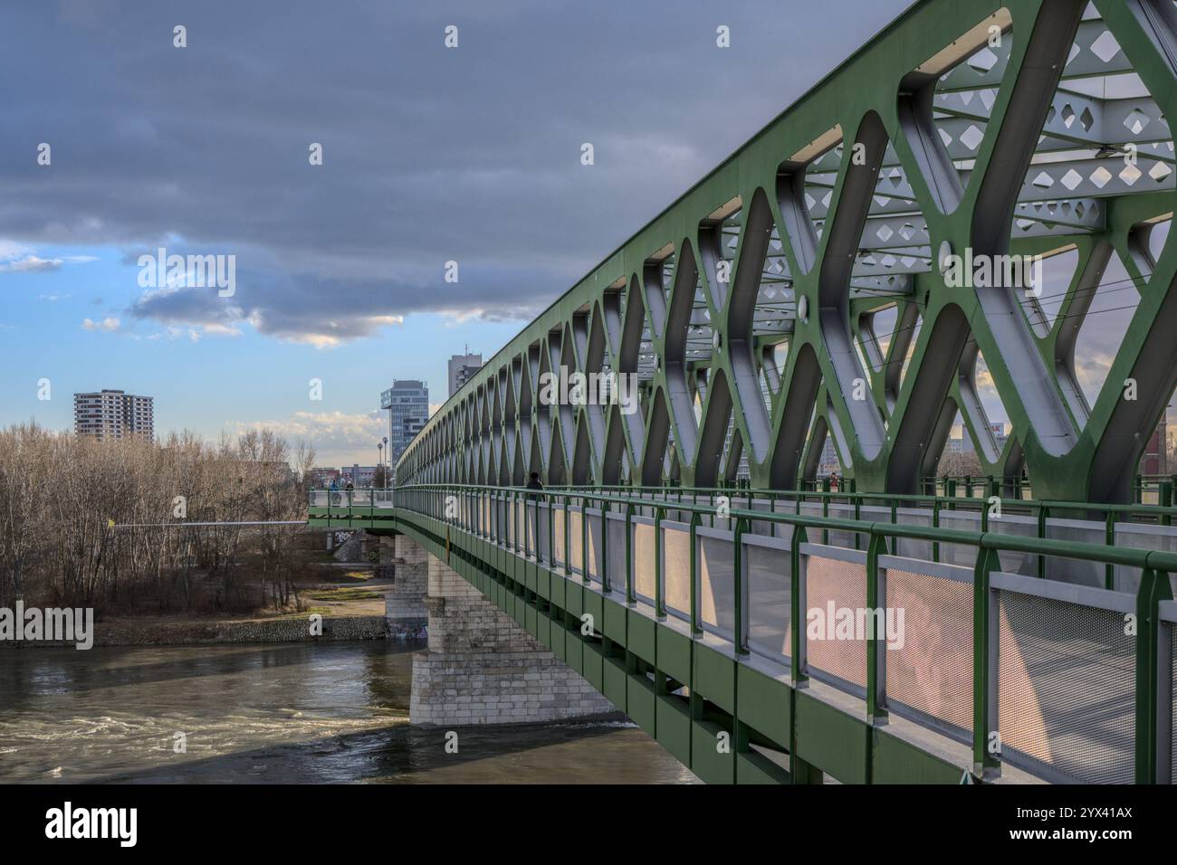 Side view of a green steel bridge crossing a river under a partly ...