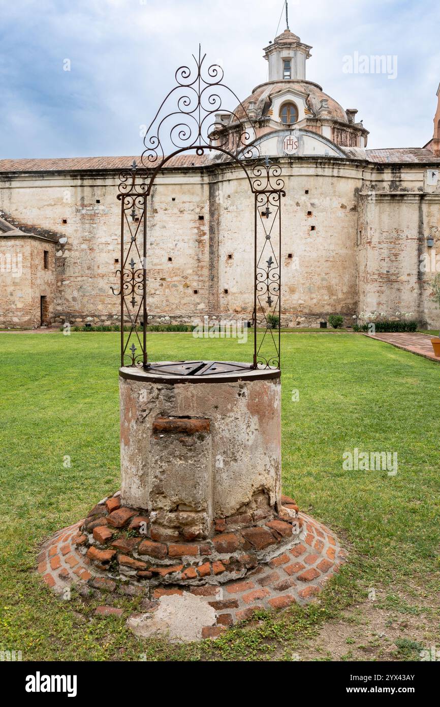 Old cistern in a garden and the dome of a church. Alta Gracia, Cordoba ...