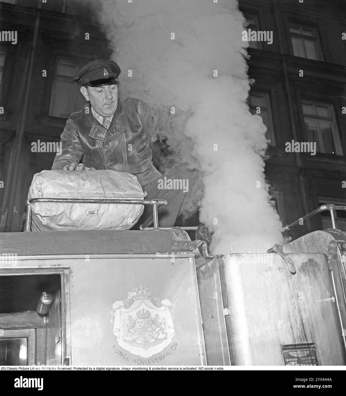 Wood gas 1942. A man fills more coal into the container to fuel the ...