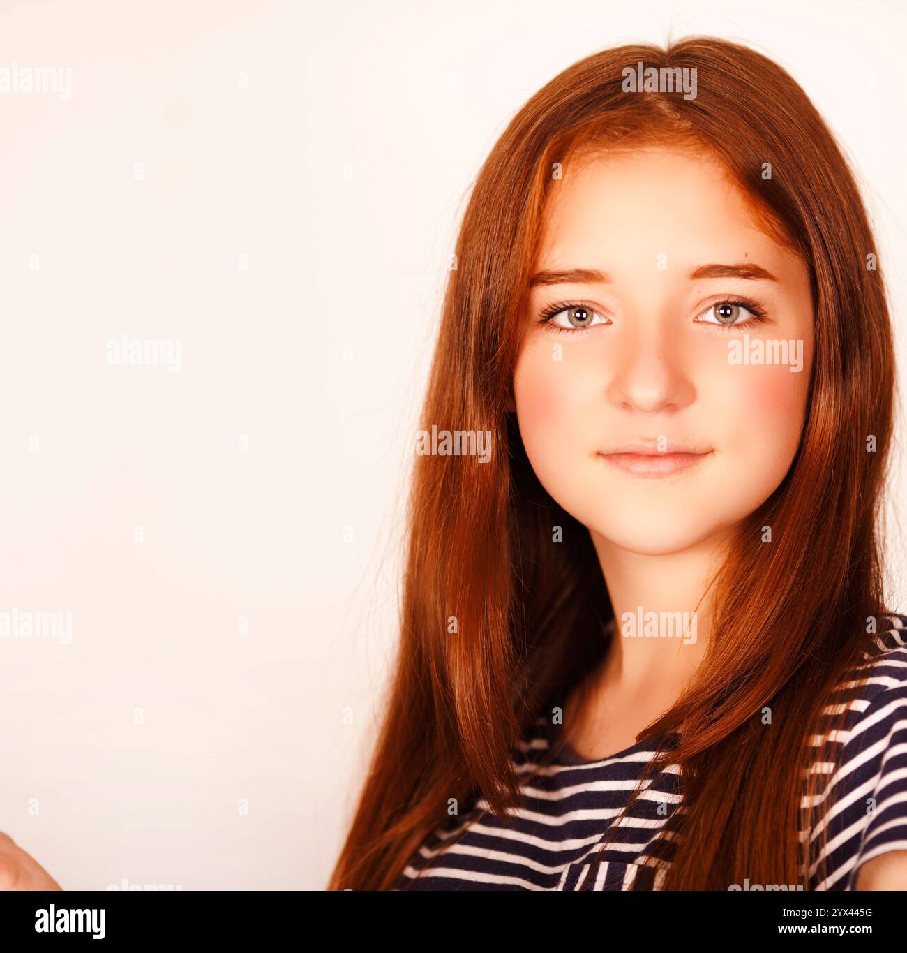 Happy beautiful girl smiling with closed eyes touching her red curly hair over white background ...