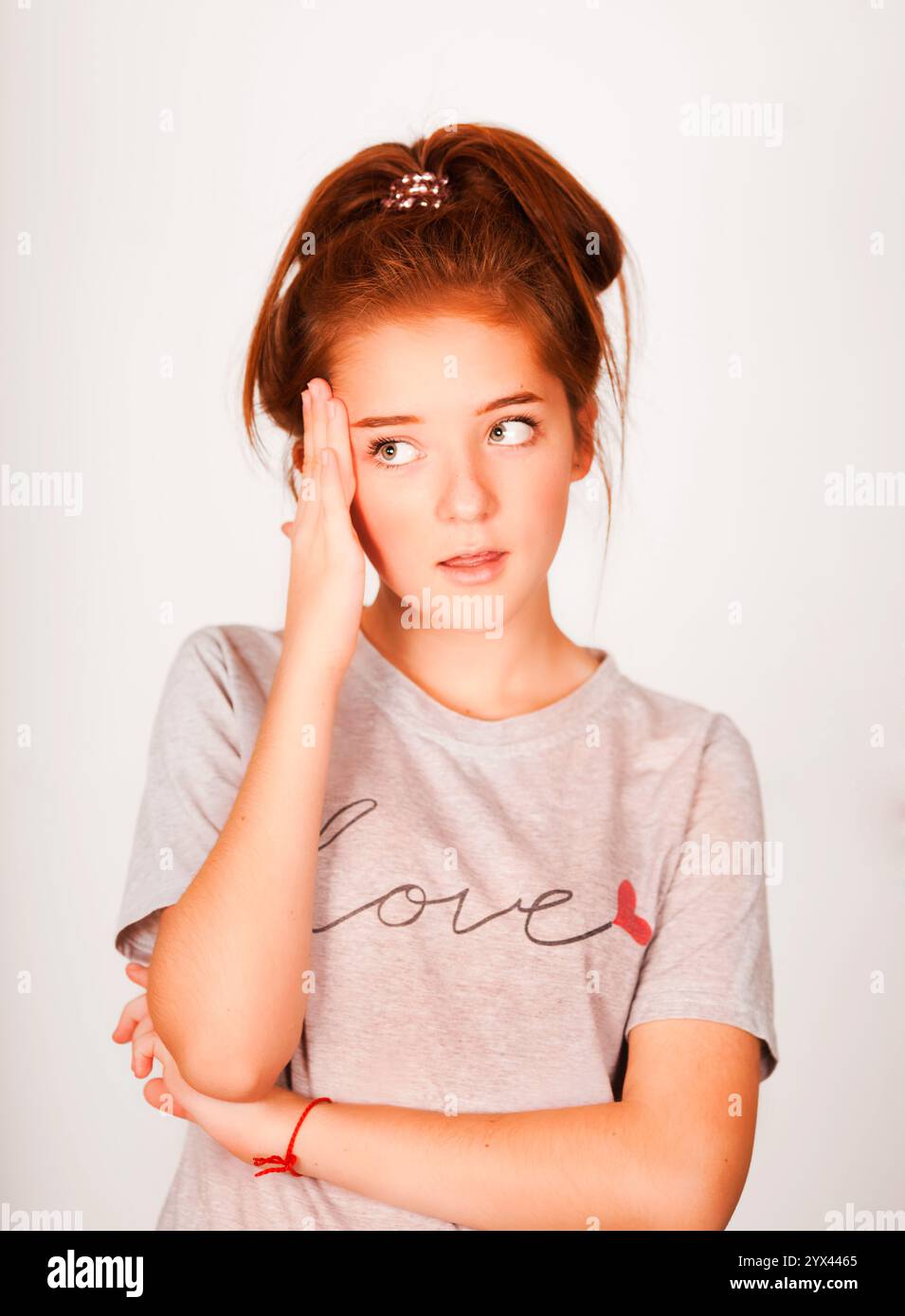 Happy beautiful girl smiling with closed eyes touching her red curly hair over white background ...