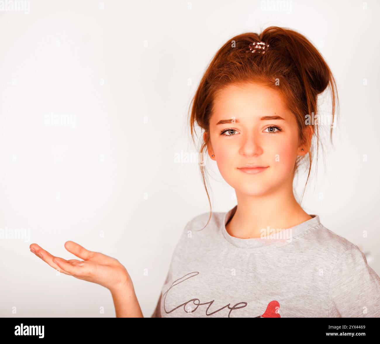 Happy beautiful girl smiling with closed eyes touching her red curly hair over white background ...