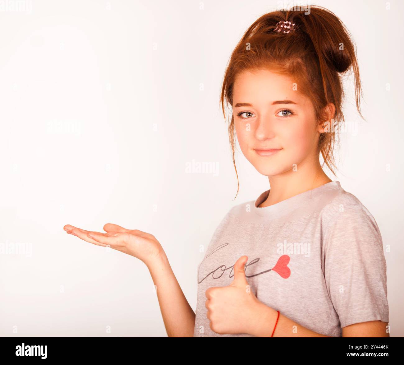 Happy beautiful girl smiling with closed eyes touching her red curly hair over white background ...