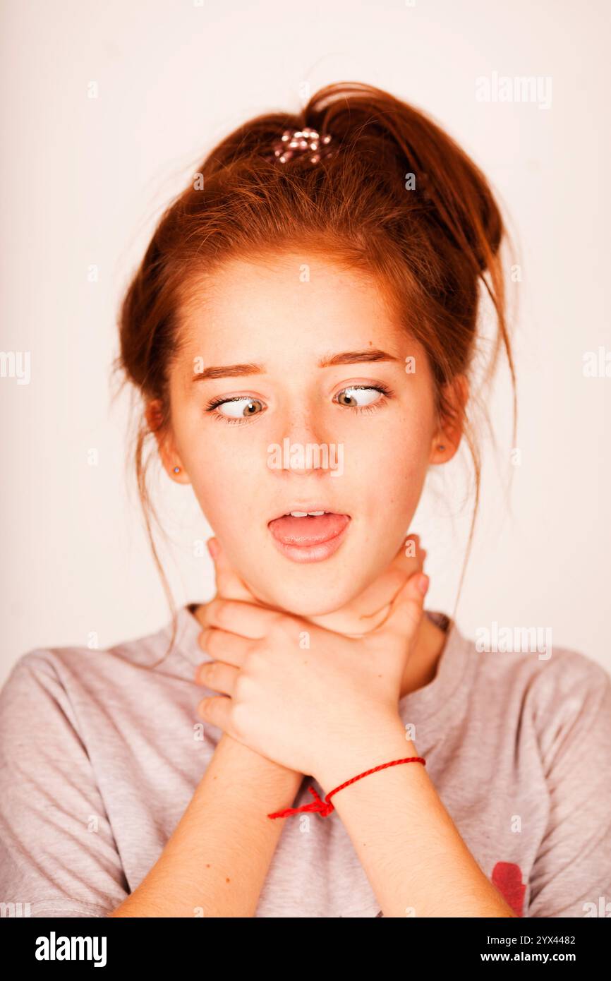 Happy beautiful girl smiling with closed eyes touching her red curly hair over white background ...
