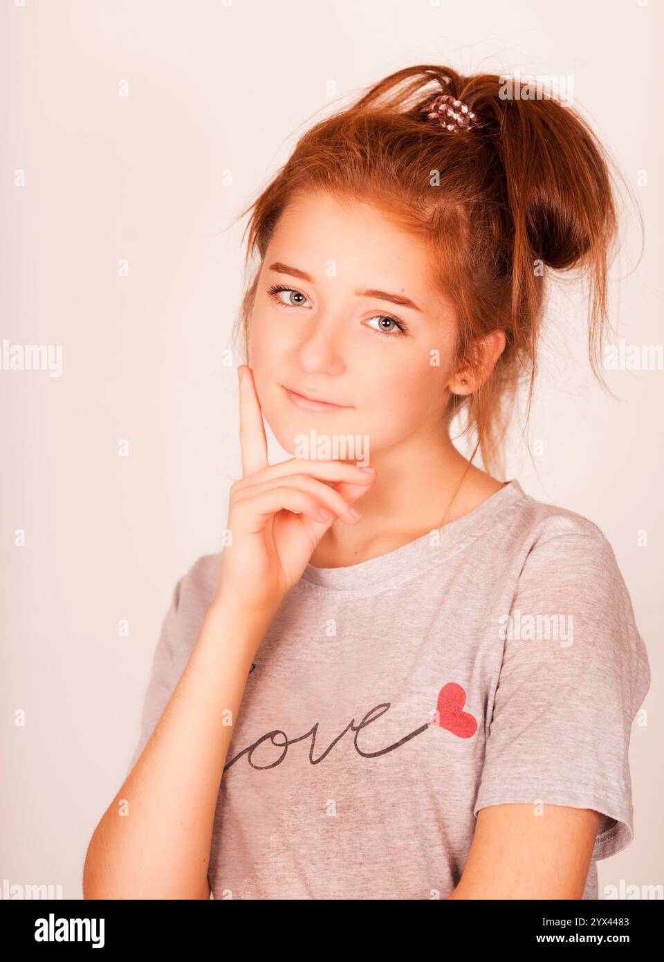 Happy beautiful girl smiling with closed eyes touching her red curly hair over white background ...