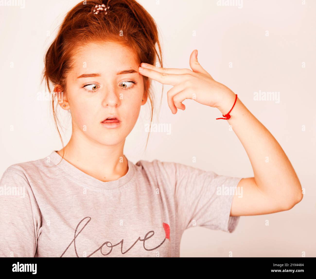 Happy beautiful girl smiling with closed eyes touching her red curly hair over white background ...