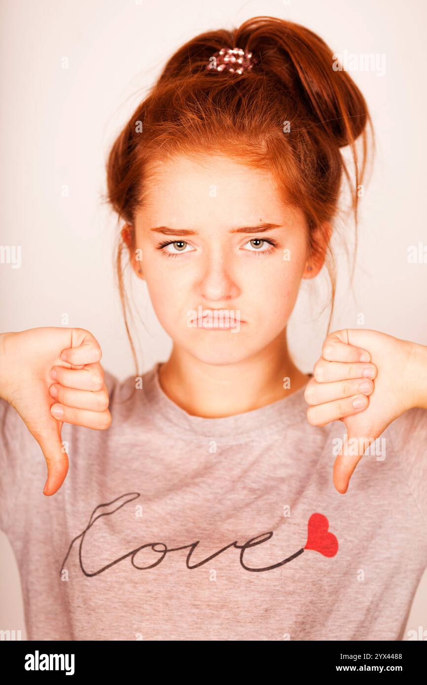 Happy beautiful girl smiling with closed eyes touching her red curly hair over white background ...
