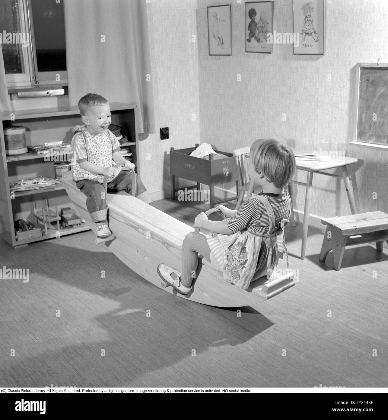 Playing indoors 1956. Two children on a seesaw in a playroom. May 1956 ...