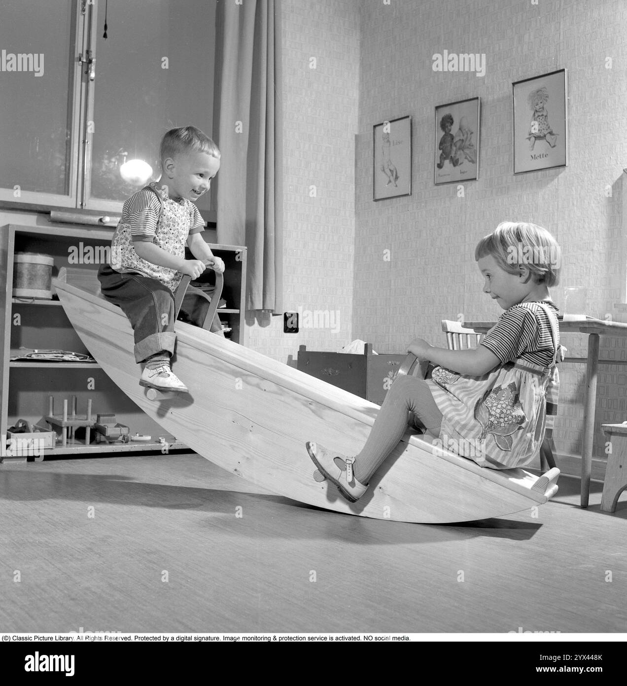 Playing indoors 1956. Two children on a seesaw in a playroom. May 1956 ...