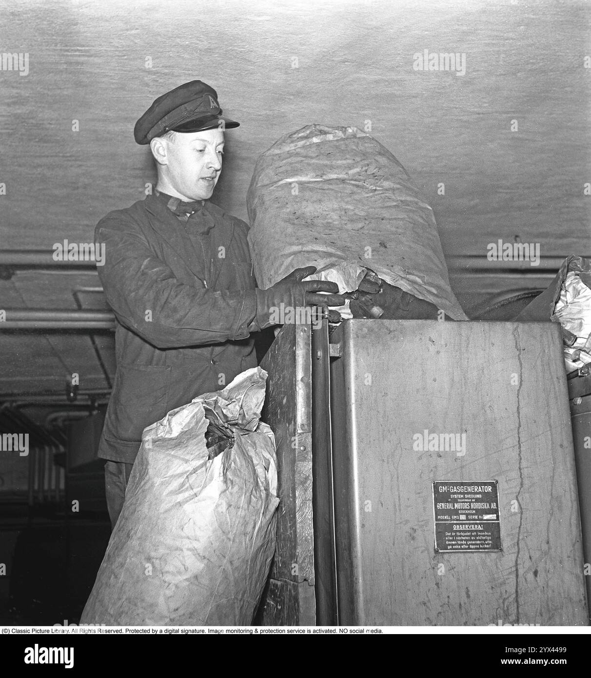 Wood gas 1942. A man fills more coal into the container to fuel the ...