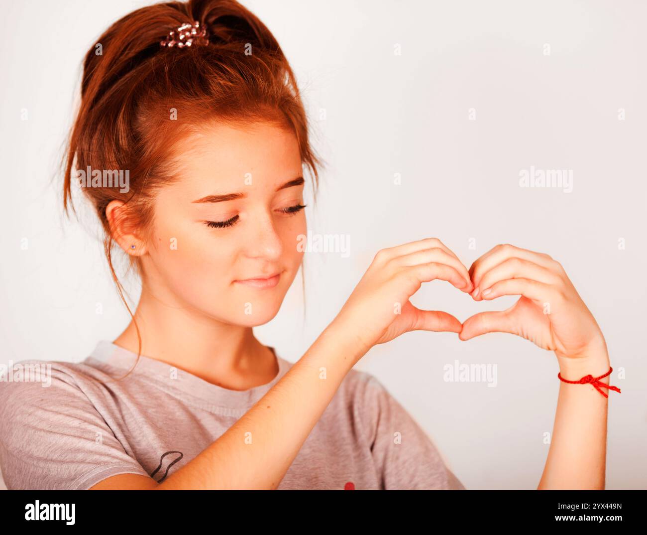 Happy beautiful girl smiling with closed eyes touching her red curly hair over white background ...