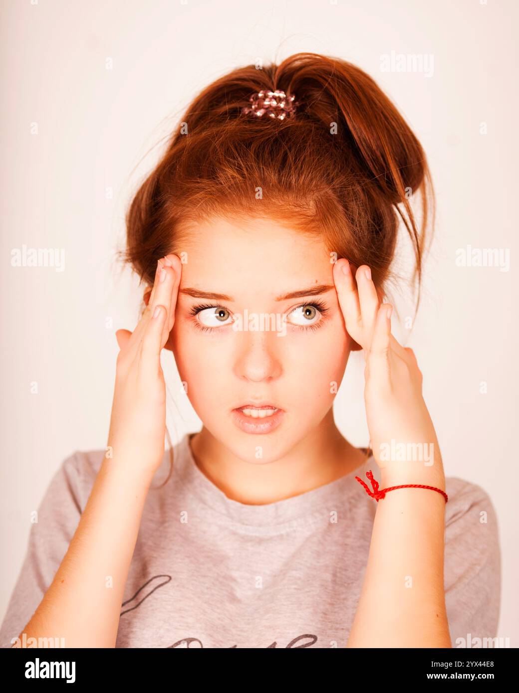 Happy beautiful girl smiling with closed eyes touching her red curly hair over white background ...
