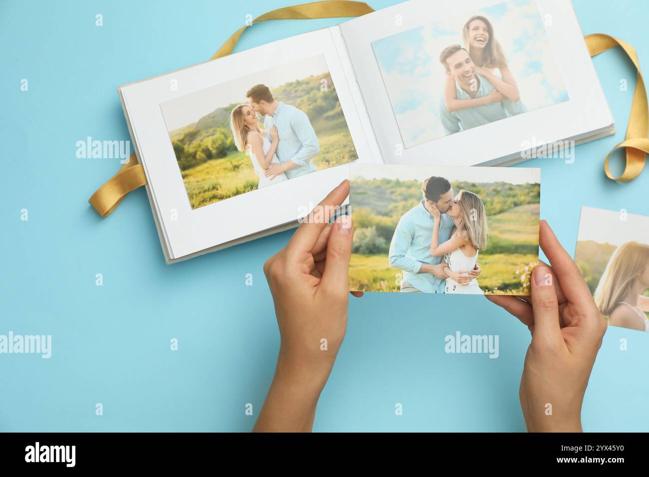 Woman with open photo album and different photos on light blue ...