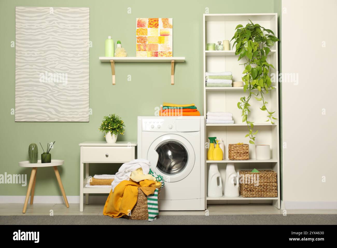 Washing machine, detergents and basket with laundry in room Stock Photo ...
