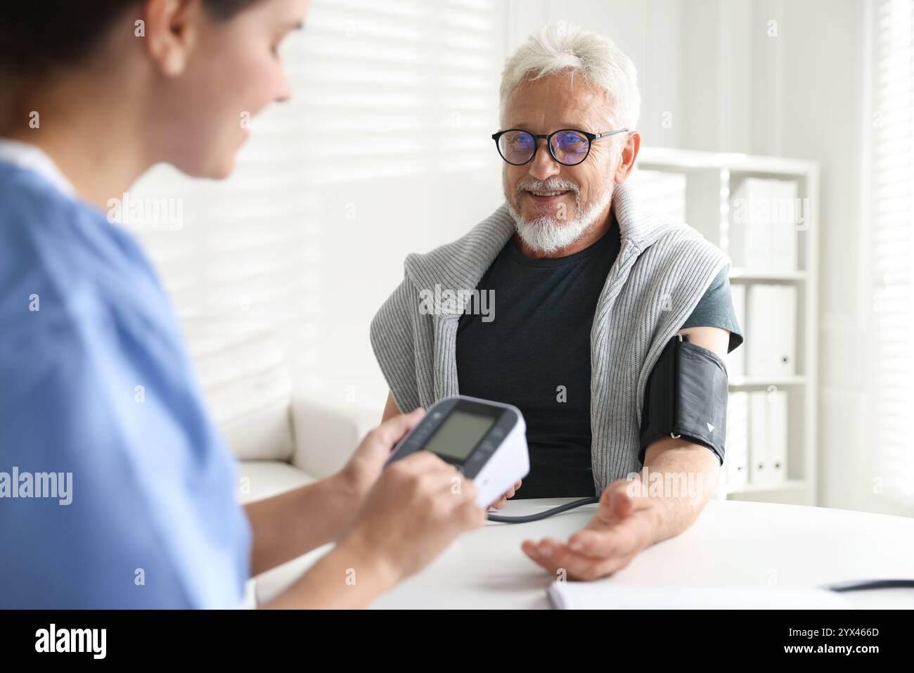Doctor measuring patient's blood pressure at table indoors Stock Photo ...