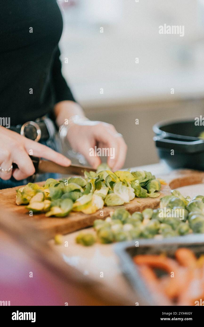 A woman is cutting up vegetables on a cutting board. The vegetables ...
