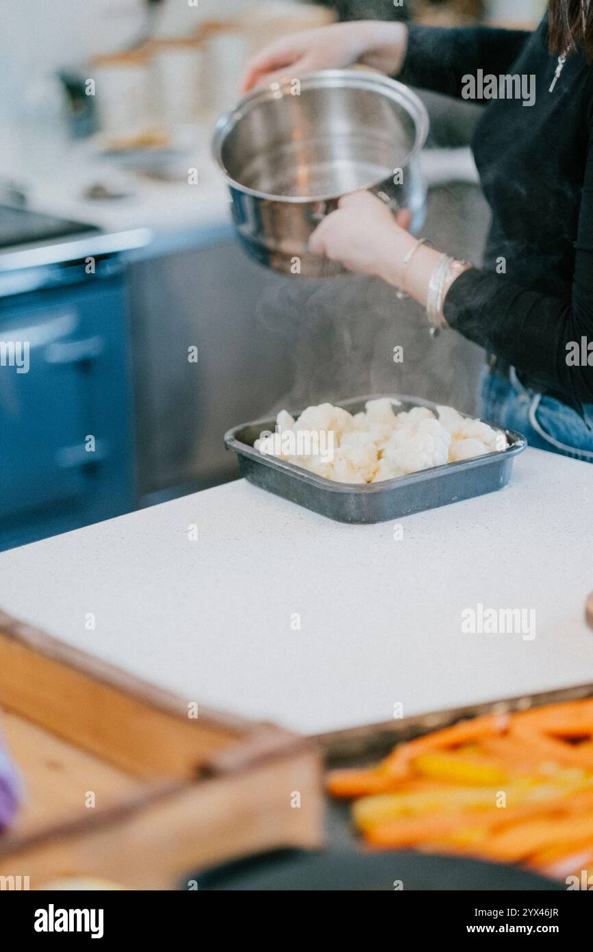 A woman is cooking vegetables in a pan. The vegetables are carrots and ...