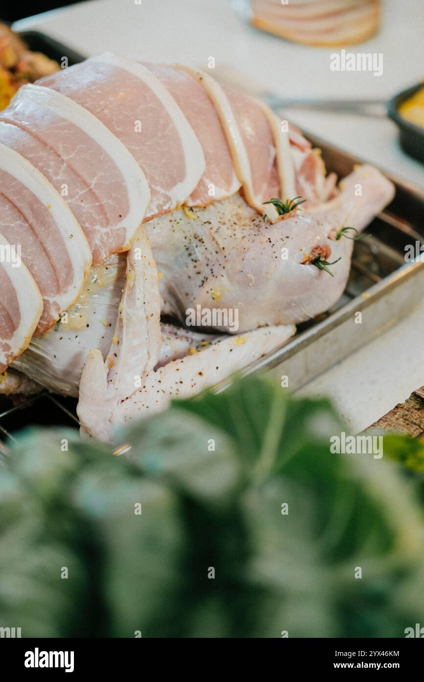 A whole roasted chicken is sitting on a pan with bacon strips on top ...