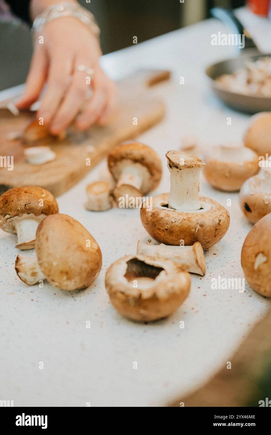 A person is cutting mushrooms on a cutting board. The mushrooms are in ...