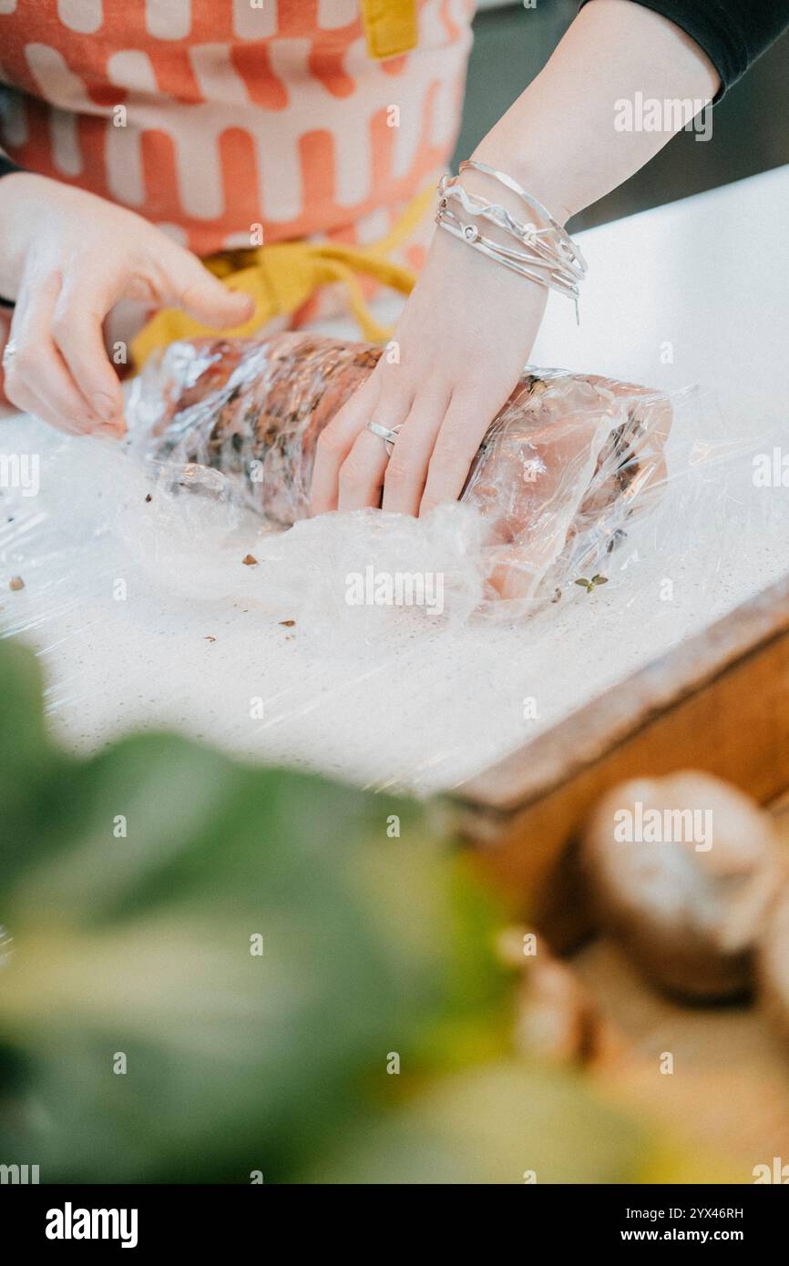 A woman is wrapping meat in plastic wrap. Concept of preparation and ...