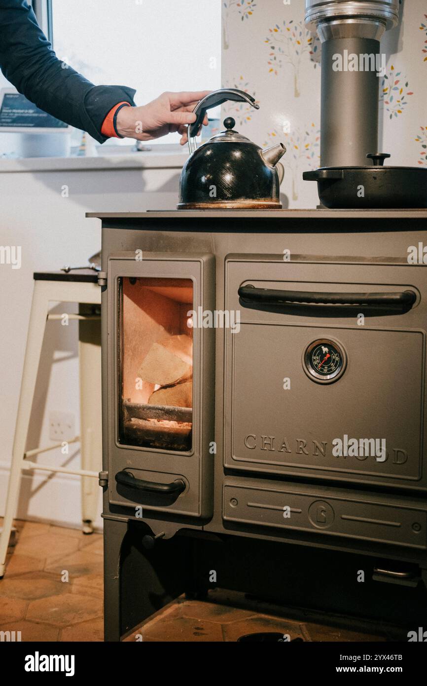 A person is pouring water into a tea kettle on a stove. The stove is ...