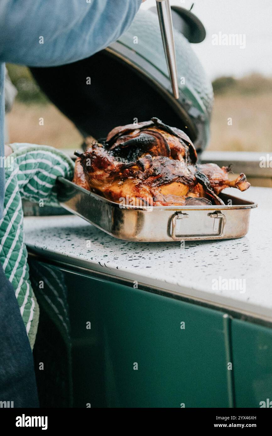 A person is cooking a turkey on a grill. The turkey is covered in bacon ...