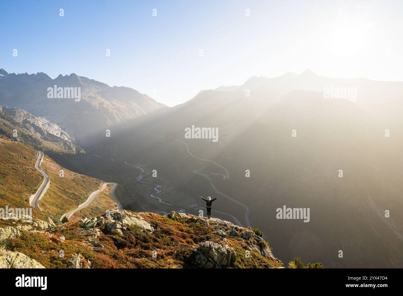 Female silhouette with raised hands standing at the edge of the cliff ...