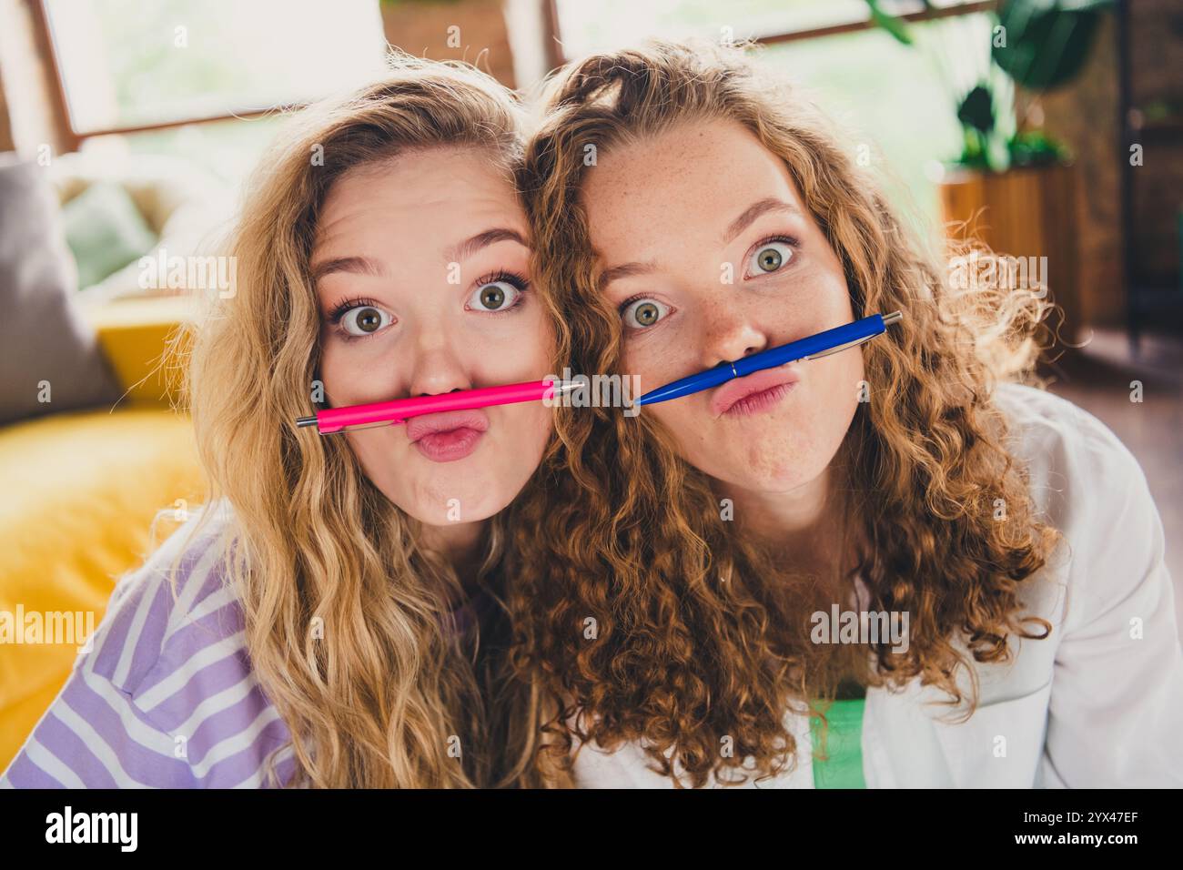 Two young girls enjoying a playful moment indoors, showcasing their ...