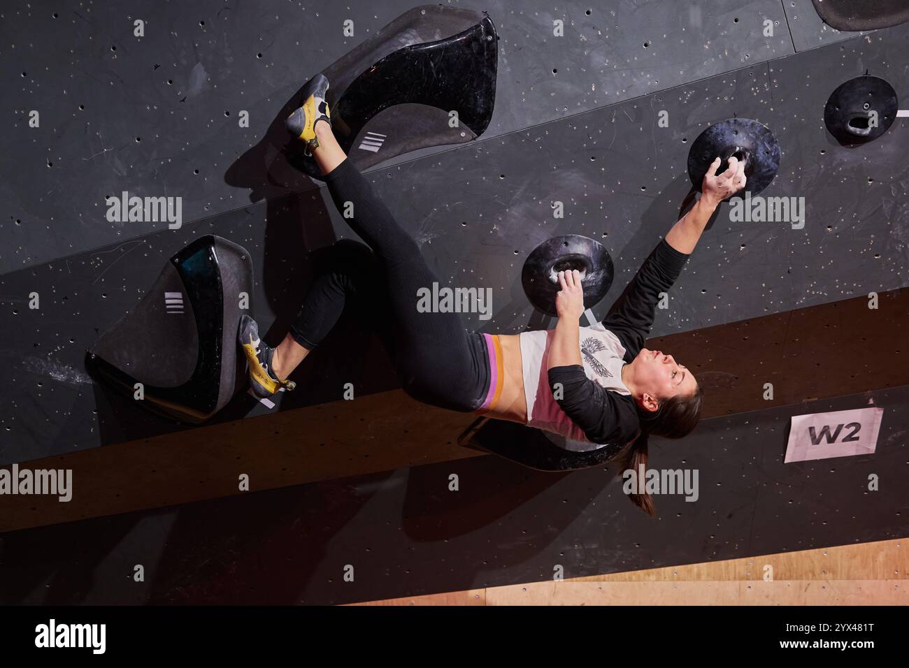 Professional climber hanging upside down on a wall in bouldering gym ...