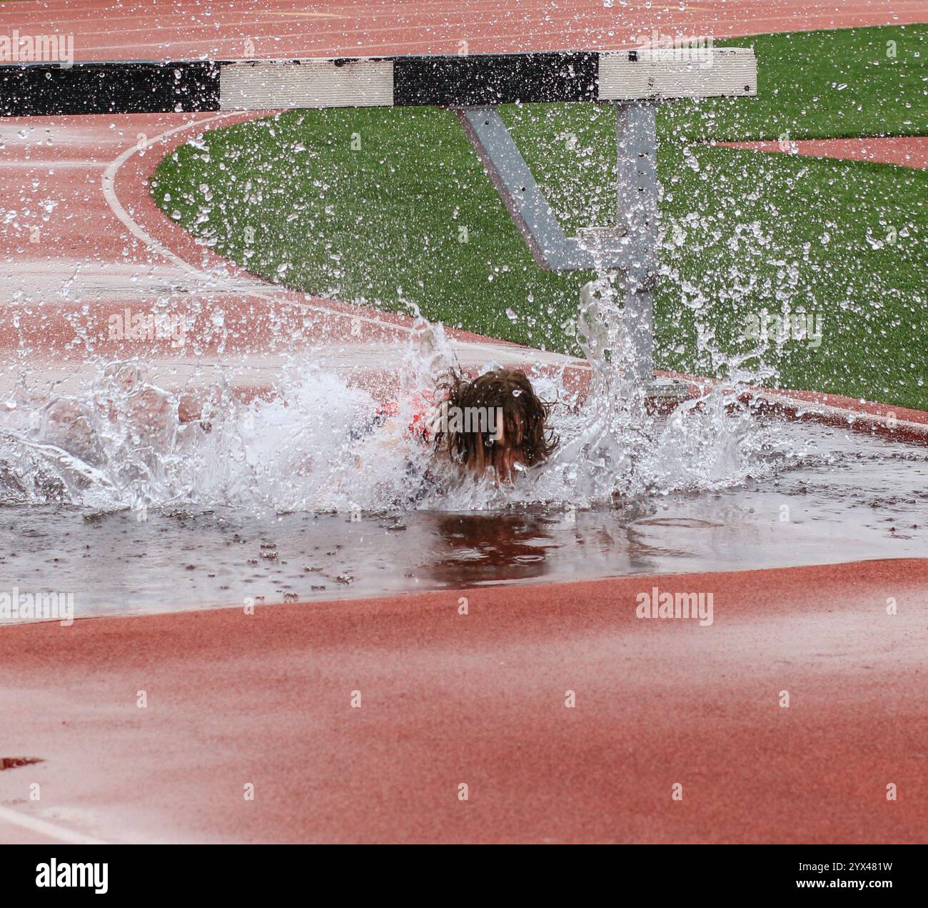 An athlete dives into a water pit while competing in a track and field ...