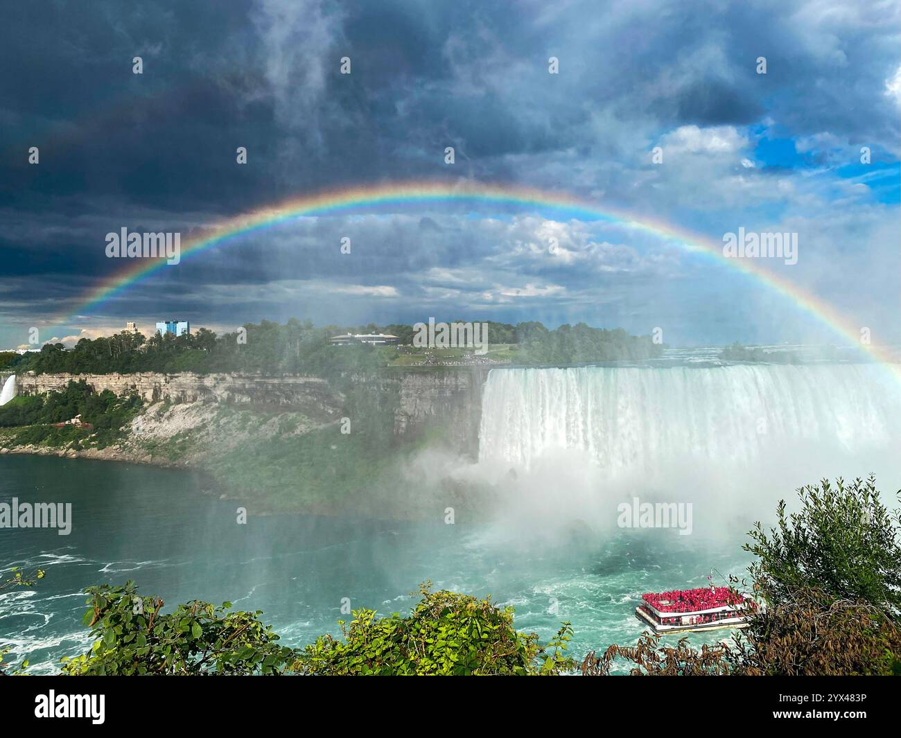 A stunning view of Niagara Falls features a bright rainbow illuminating ...