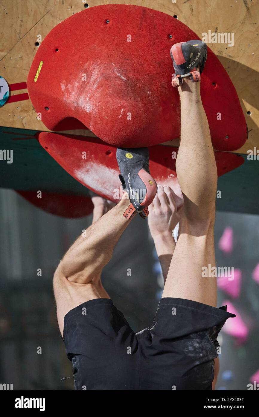 Feet of a climber hanging upside down on a wall in indoor climbing gym ...