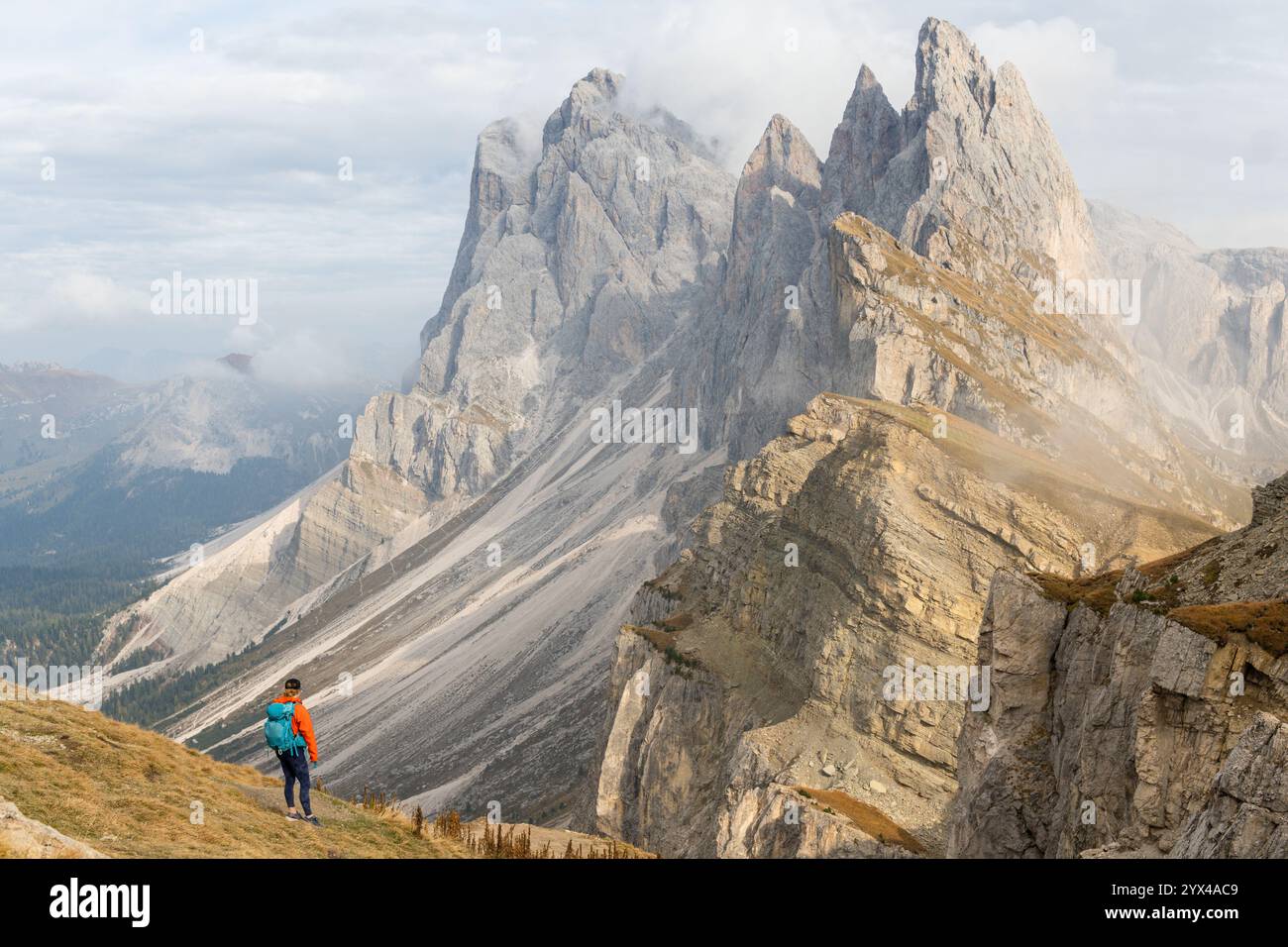 Woman in bright raincoat standing in front of Seceda mountain in ...