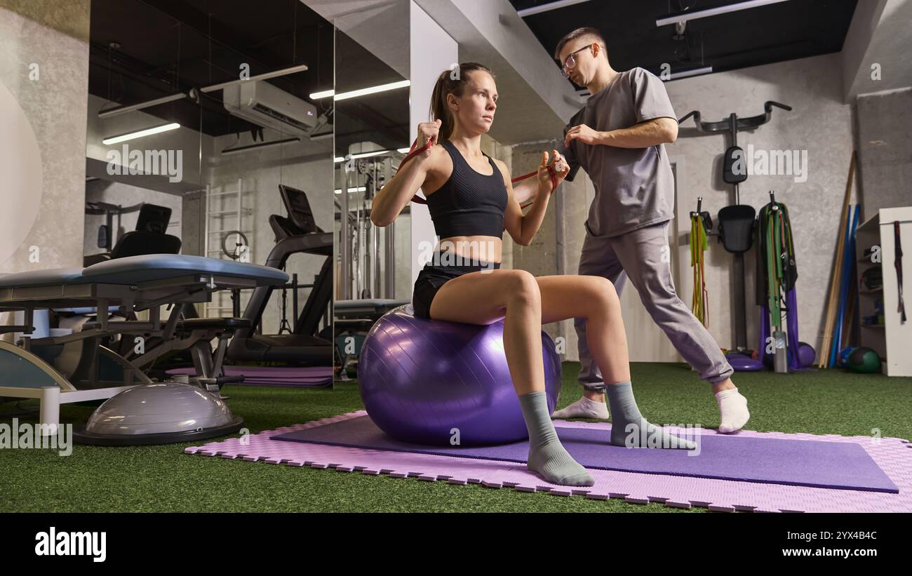 Female patient performing resistance band exercises on purple stability ...